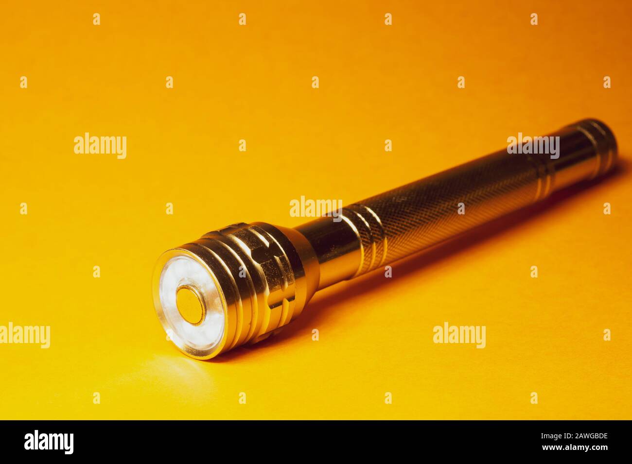 Metal flashlight on a yellow background Stock Photo - Alamy