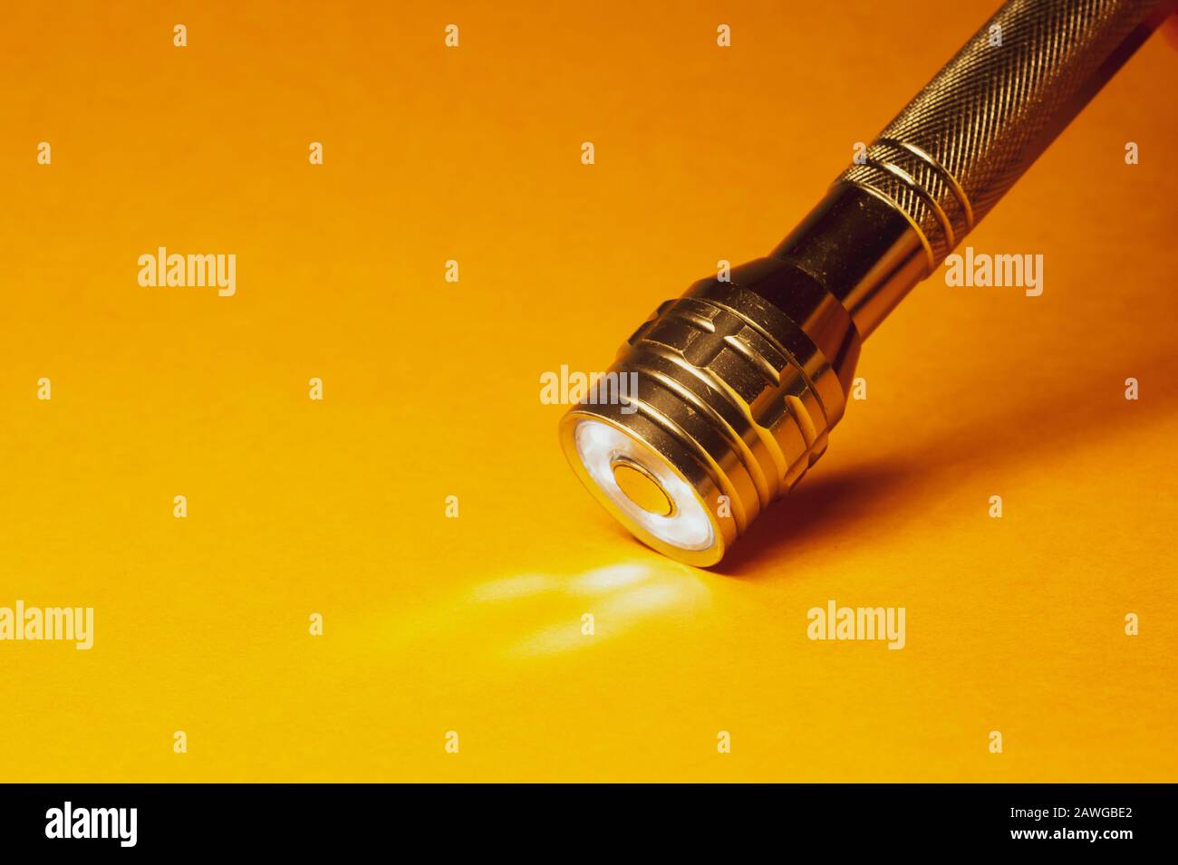 Metal flashlight on a yellow background Stock Photo - Alamy