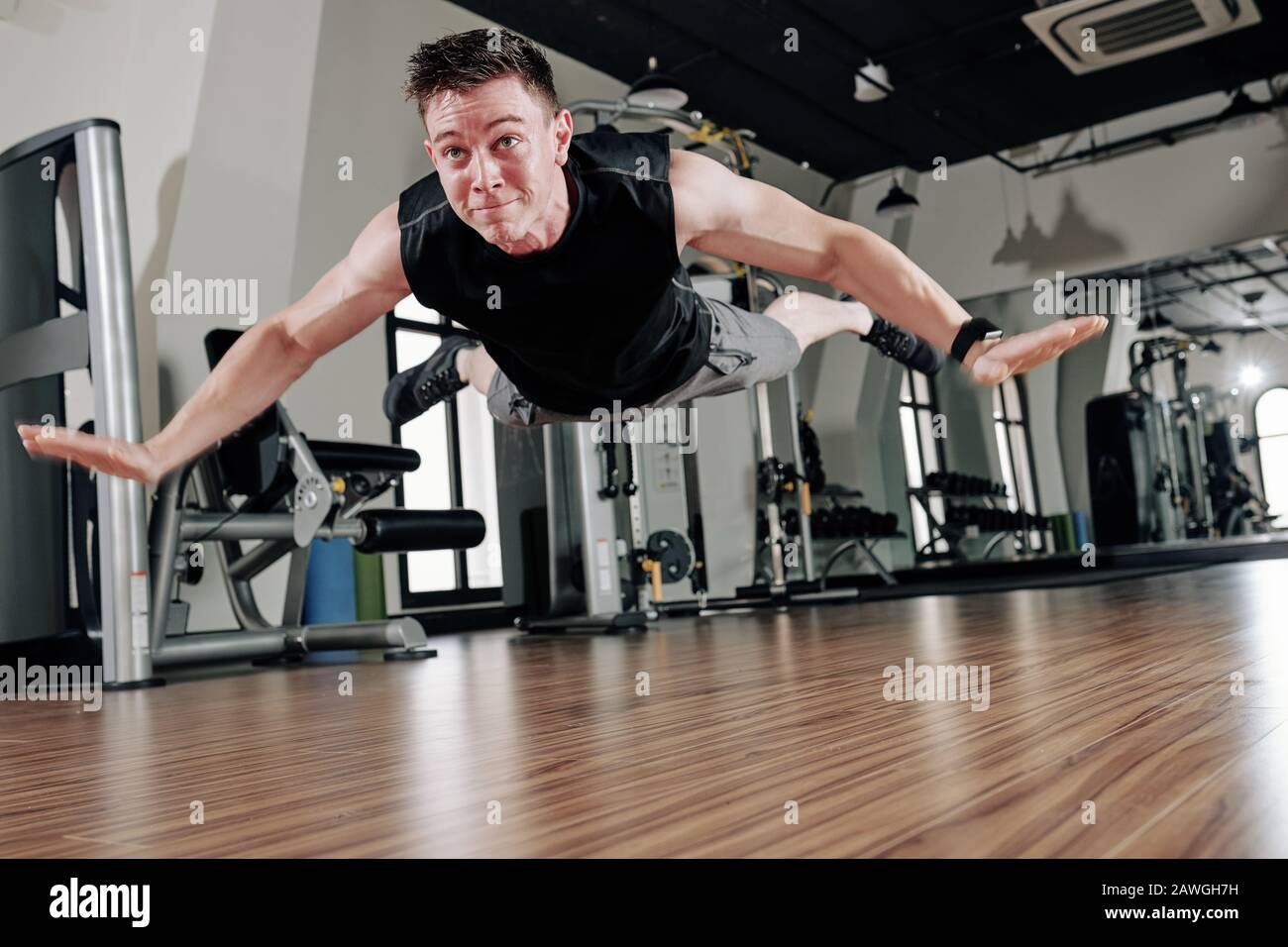Fit young man doing kip-up movement in gym Stock Photo - Alamy