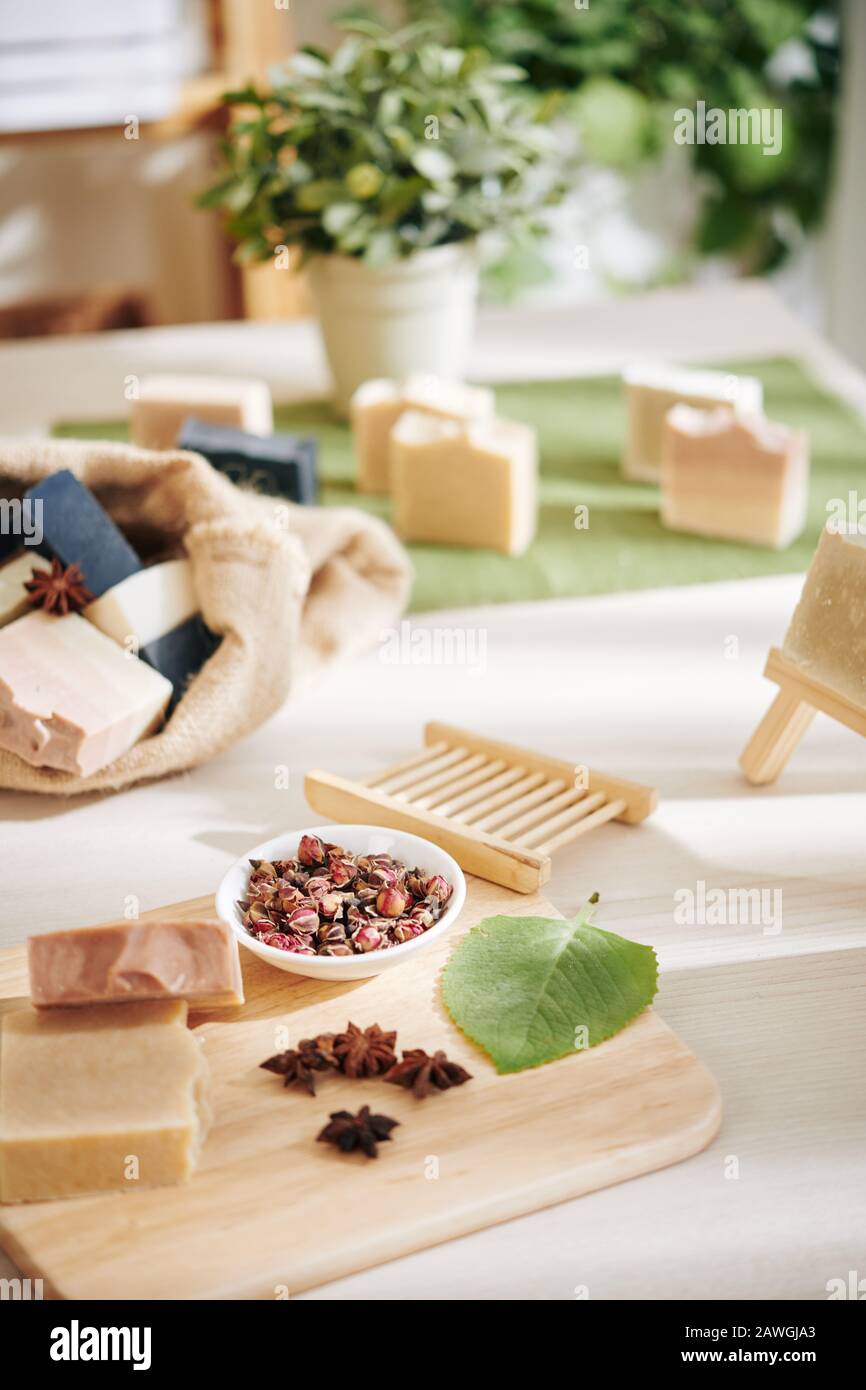 Ingredients and homemade soap bars on table in natural cosmetics store ...