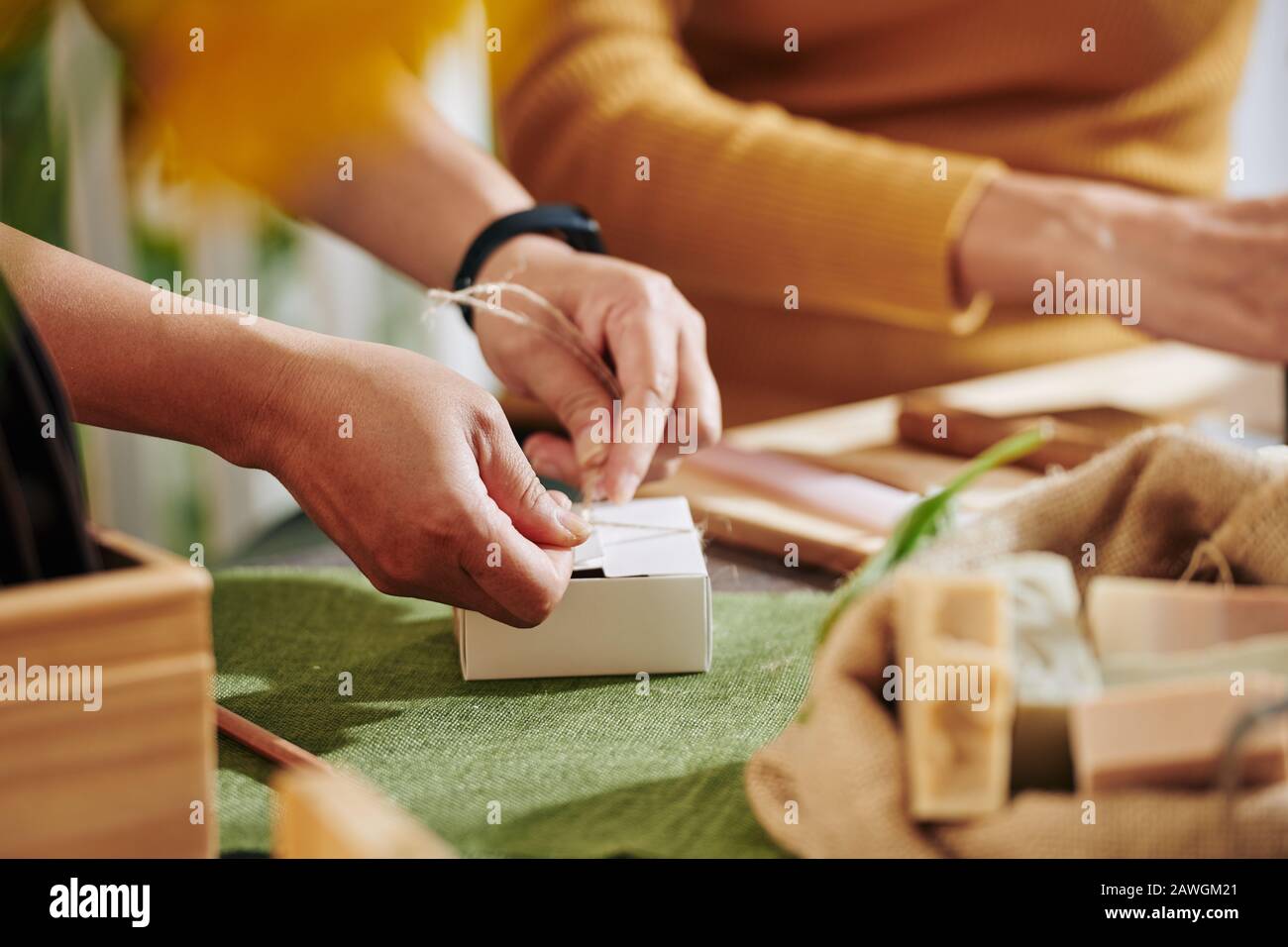 Women packing small soap bars in cardboard boxes to send it to ...