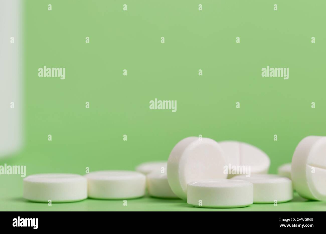 White round medicine pills. Green homogeneous background. At the top of ...