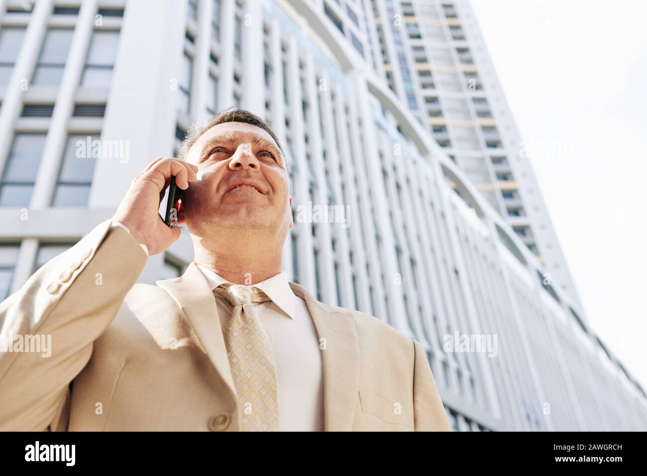 Middle-aged businessman standing outside the office building and ...