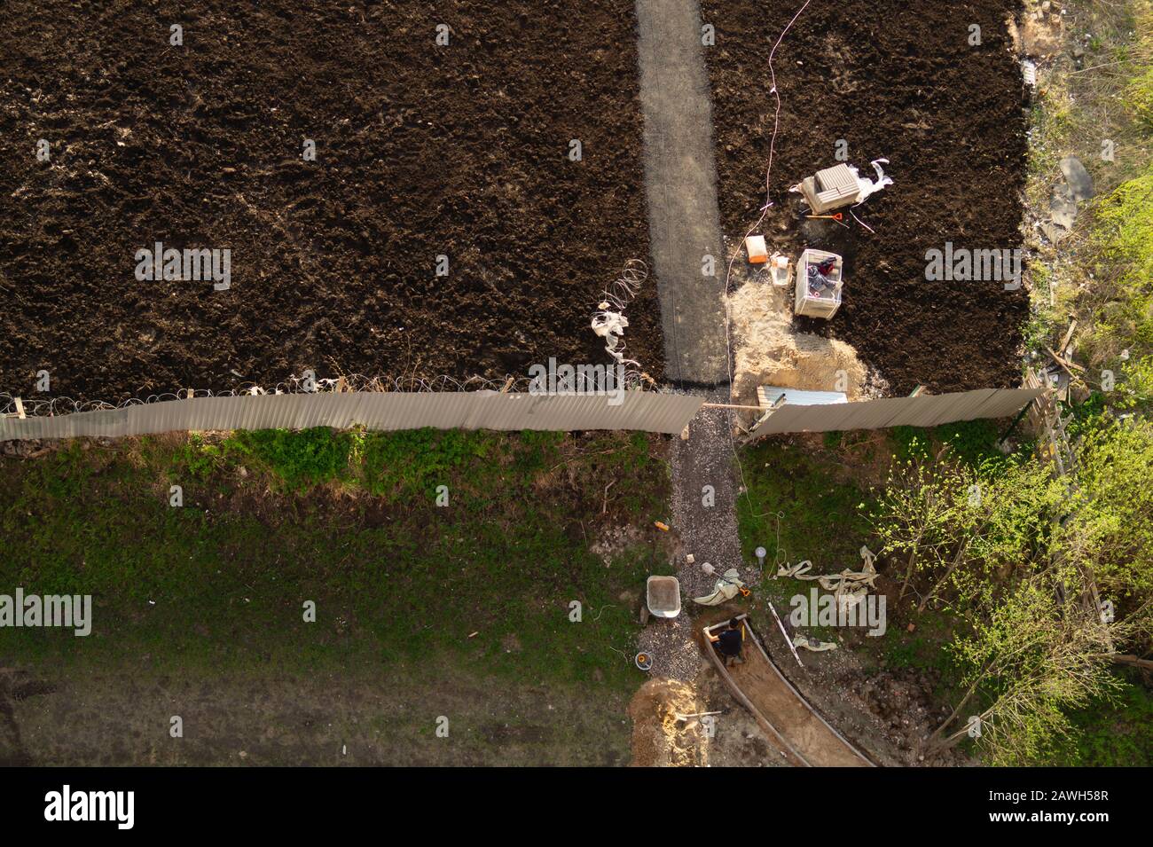 Worker manually makes a way to future parking lot. builder is busy with ...