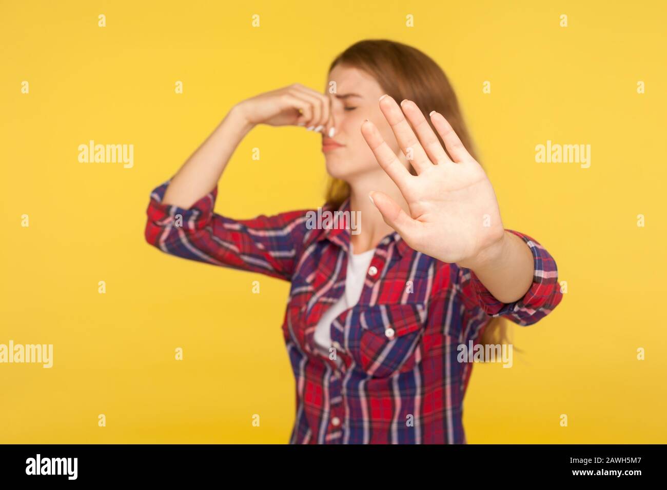 Bad smell. Portrait of displeased ginger girl in checkered shirt ...