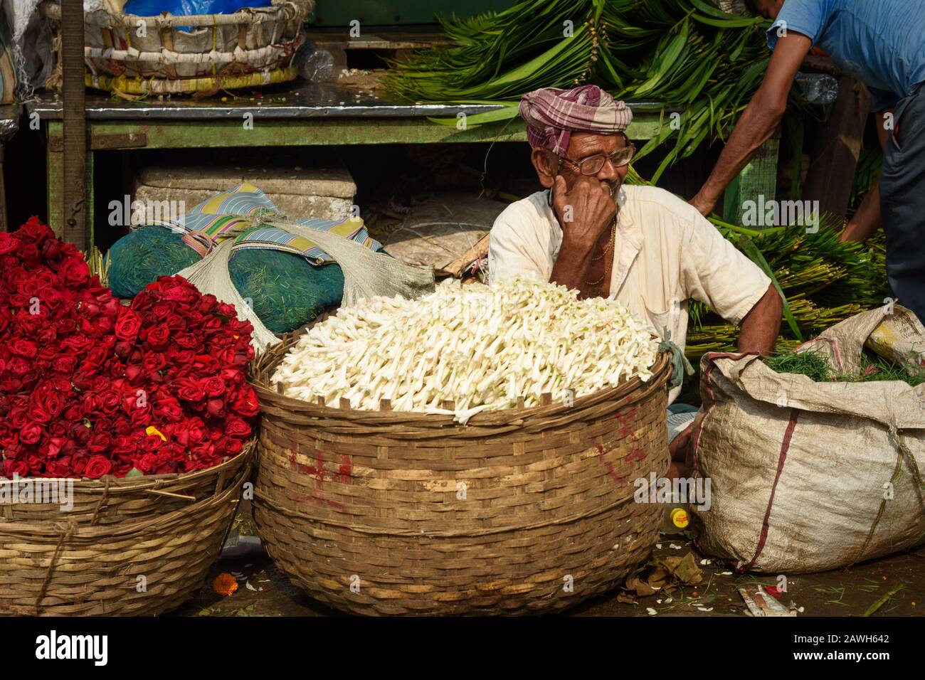 Indian seller with flower and garland in baskets on Flower market at ...
