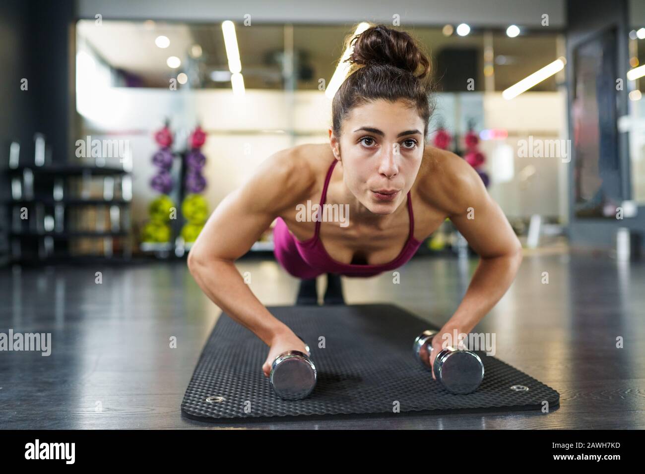 Woman doing push-ups exercise with dumbbell in a fitness workout Stock ...