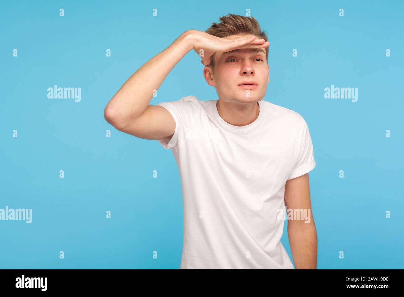 Far away vision. Portrait of inquisitive man in casual white t-shirt ...