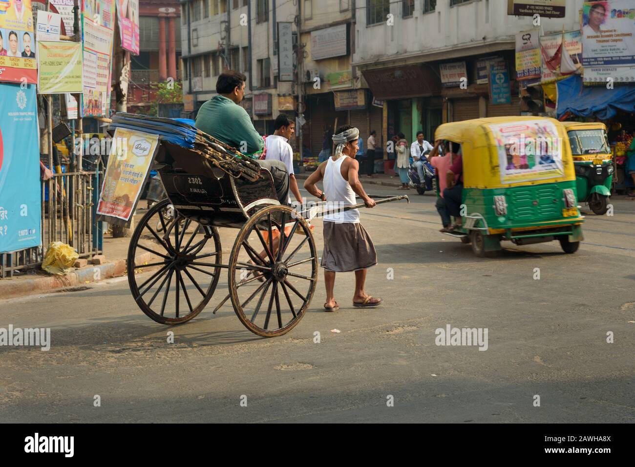 Man rickshaw puller is pulling his hand rickshaw with passenger on the ...