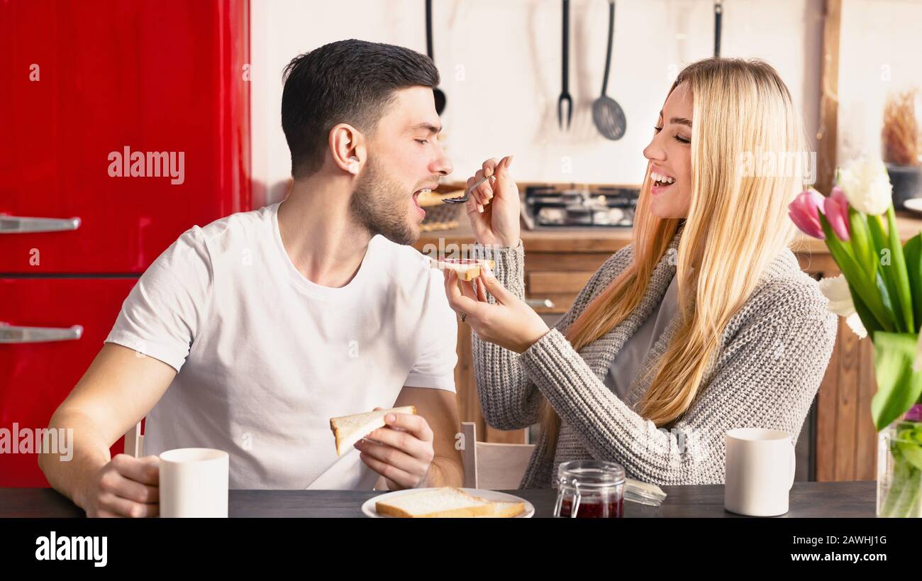 Beautiful young couple is eating sandwiches and smiling Stock Photo - Alamy