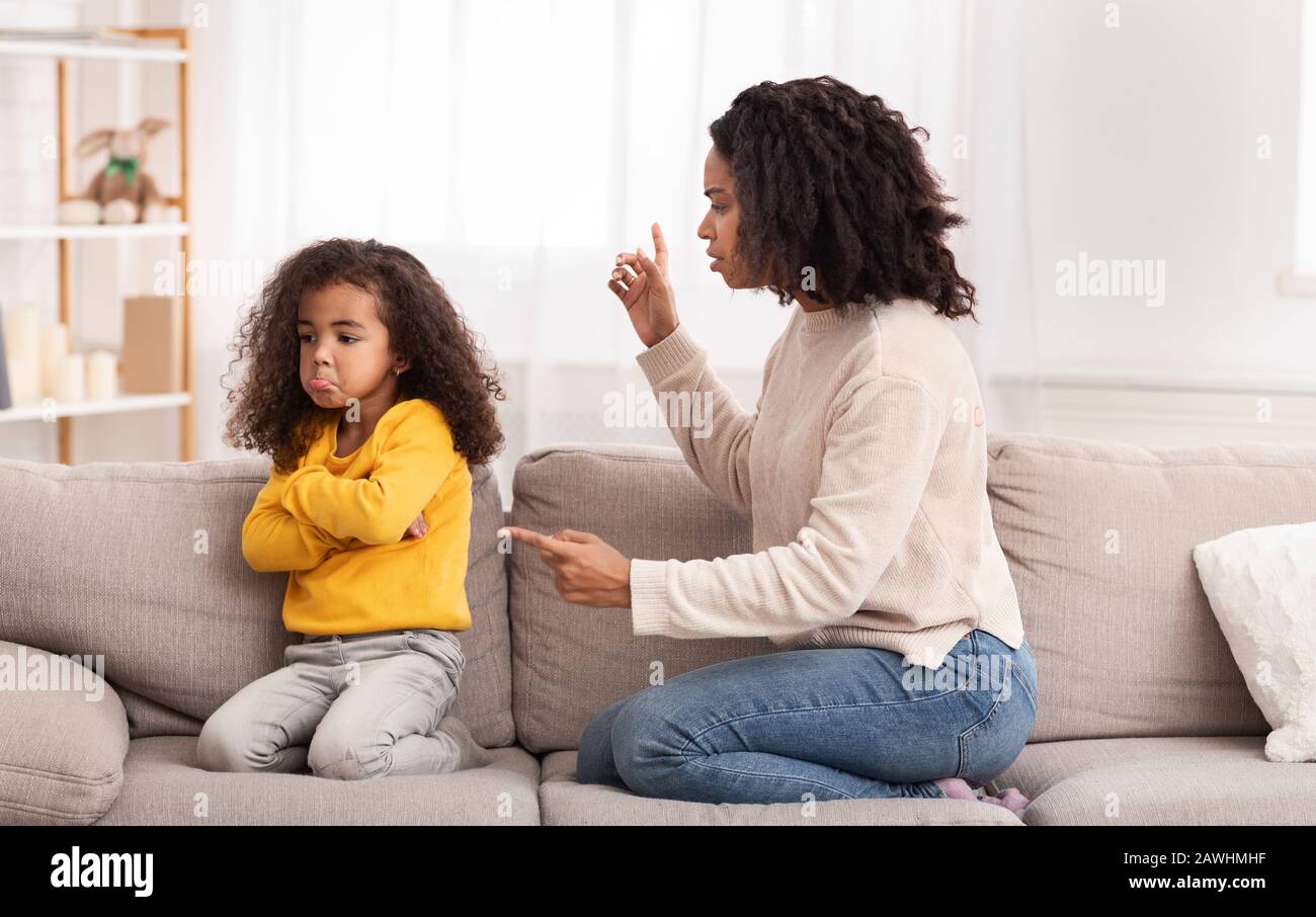 Black Mother Scolding Daughter Sitting On Sofa At Home Stock Photo - Alamy