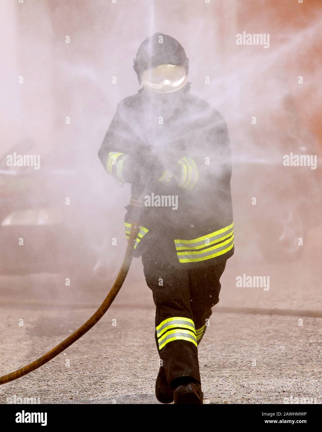 firefighter with an helmet uses a foaming agent to extinguish a fire ...