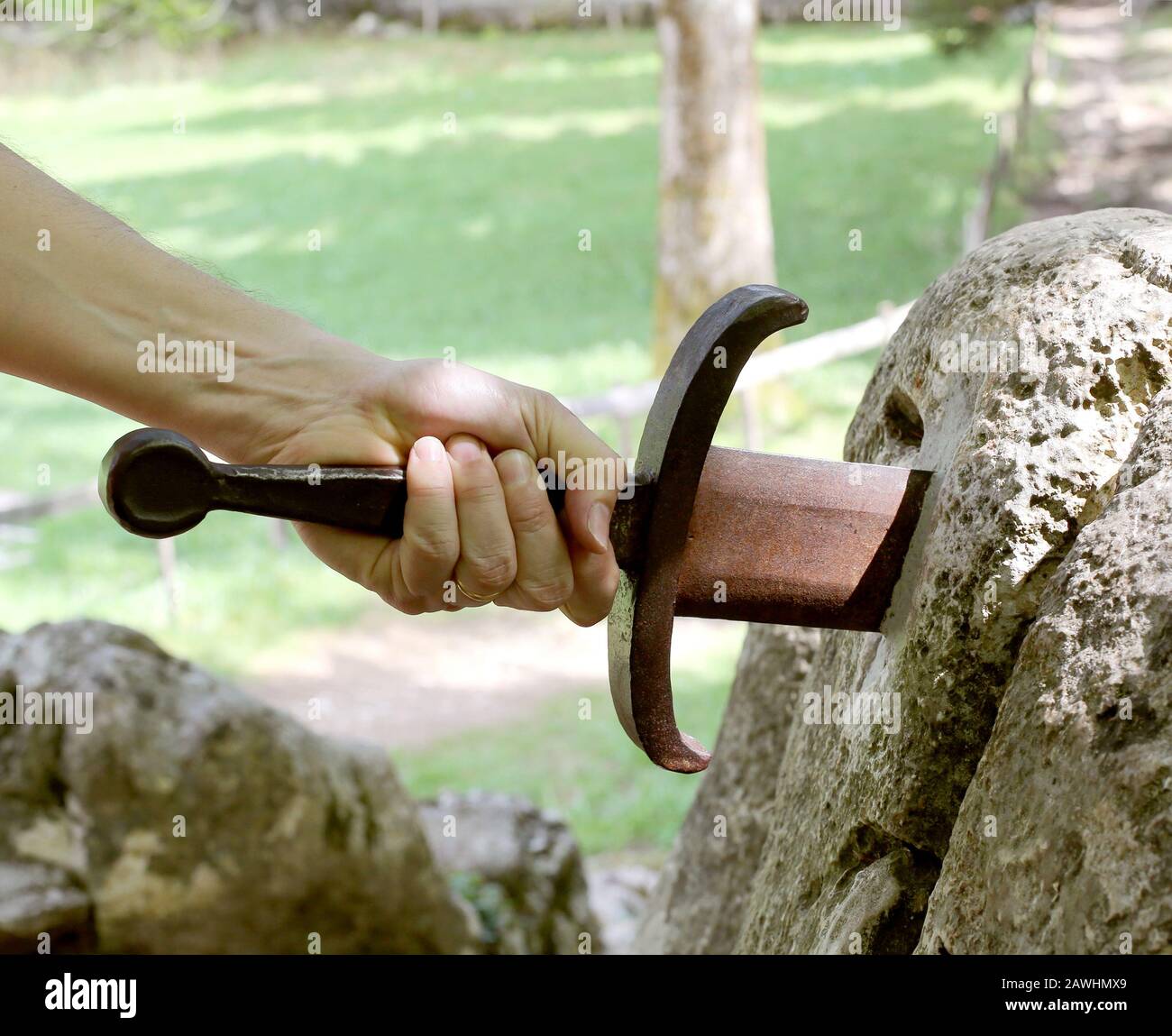 Excalibur Sword in the stone nad the hand of a man that tries to remove ...