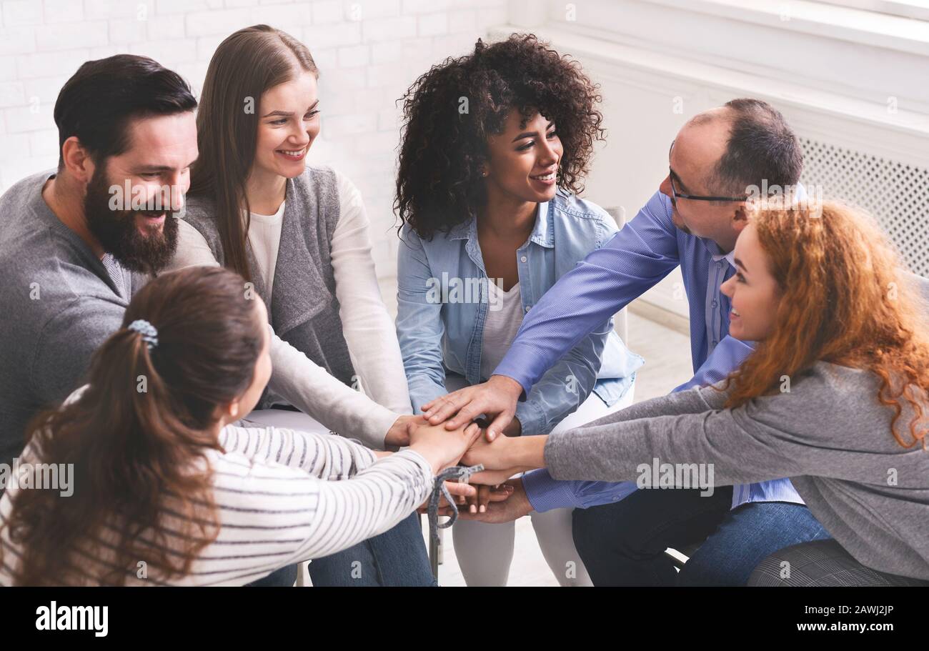 Group Of Happy People Joining Hands At Therapy Session Stock Photo - Alamy