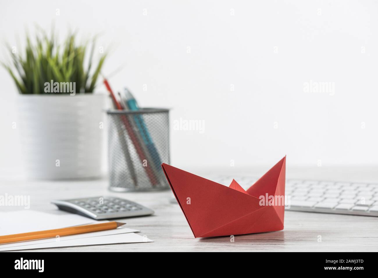 Wooden office desk with red origami boat Stock Photo - Alamy