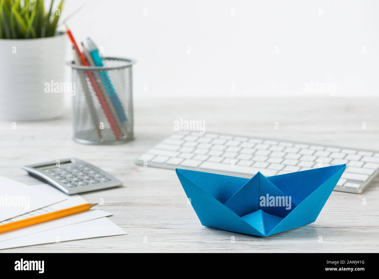 Wooden office desk with deep blue origami boat Stock Photo - Alamy