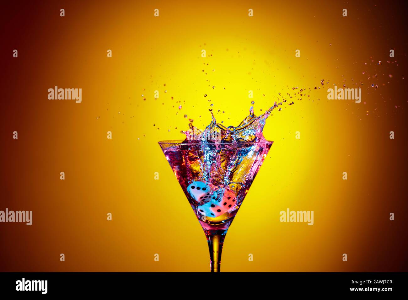 Dice fall in a glass of martini. Colourful cocktail in glass with ...