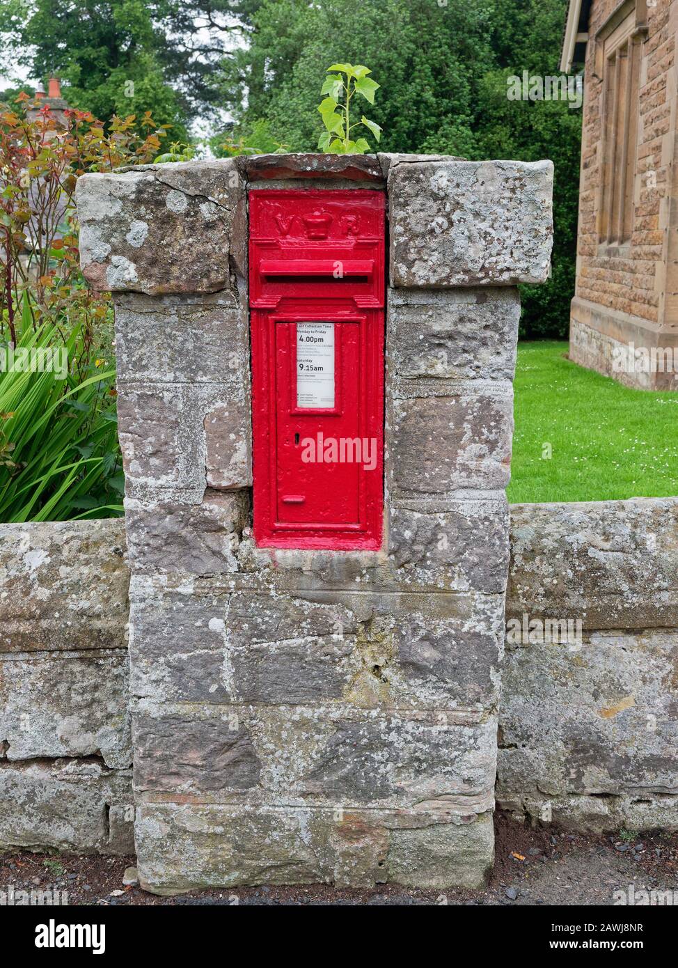 An Old cast Iron Traditional red Post Box set into the Stone Buttress ...