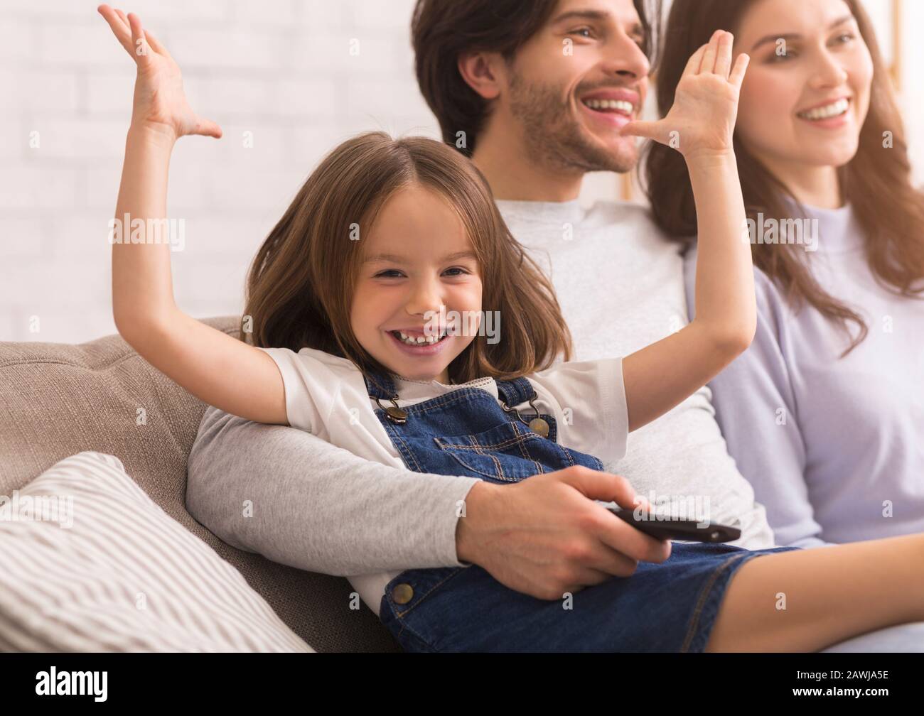Joyful Little Girl Raising Hands And Smiling Next To Parents Stock ...