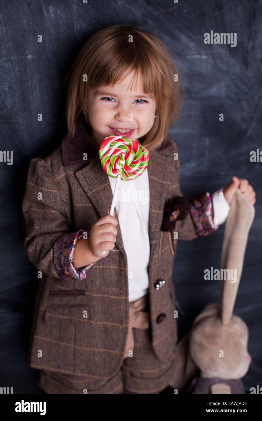 Beautiful Happy little girl with toy eating lollipop Stock Photo - Alamy