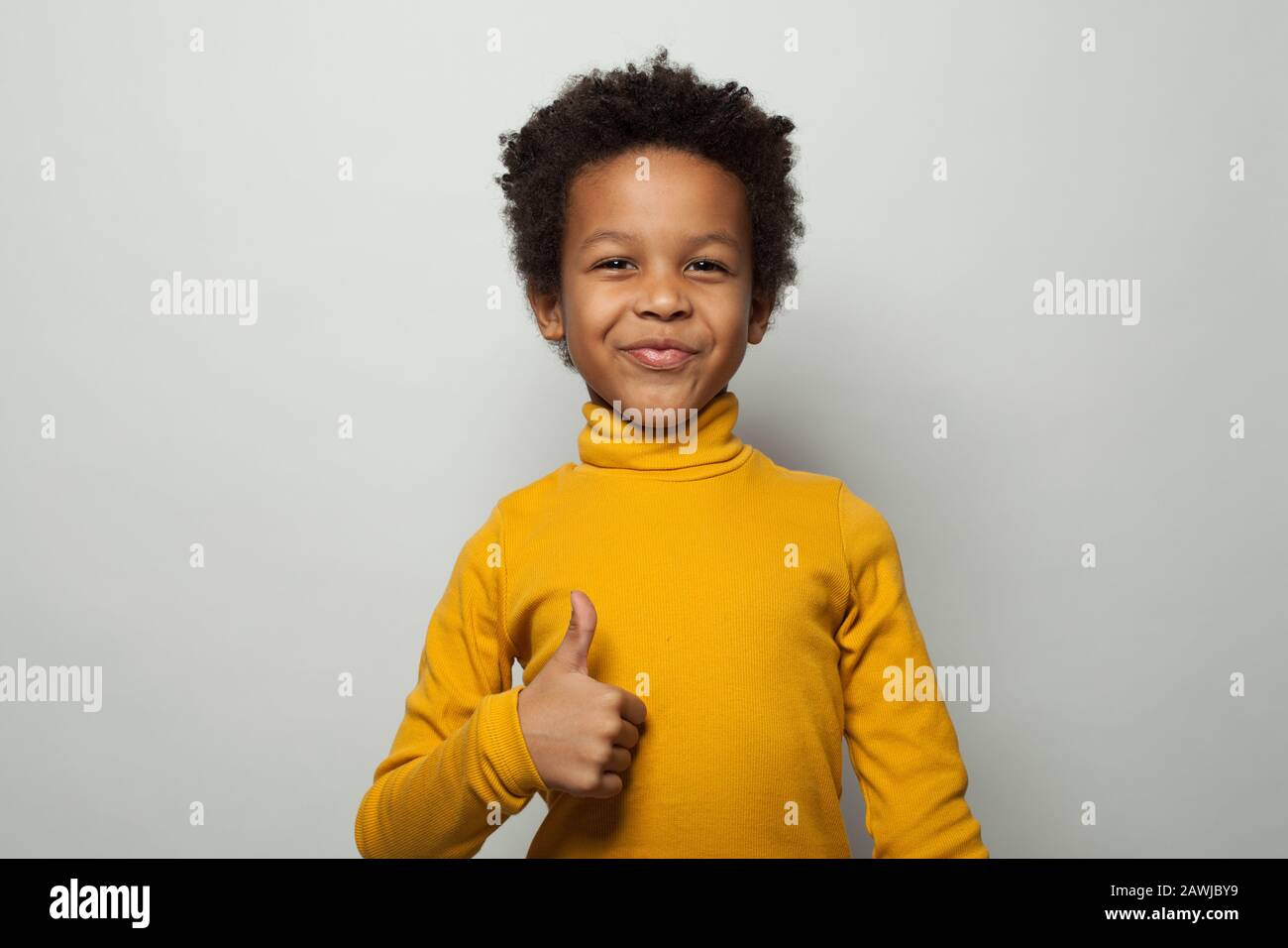 Small optimistic black child boy smiling and showing thumb up on white ...