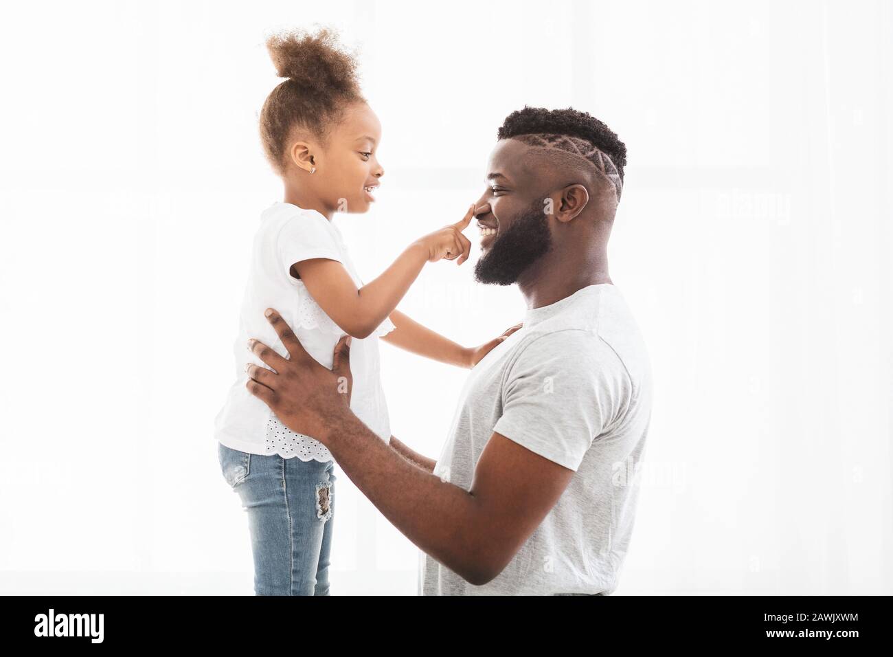 Curious afro girl touching her dad nose Stock Photo - Alamy