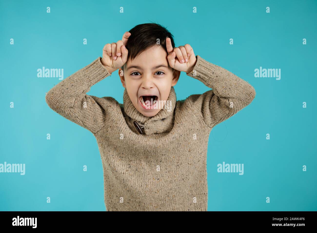 happy funny little child boy doing funny gesture with finger over head ...