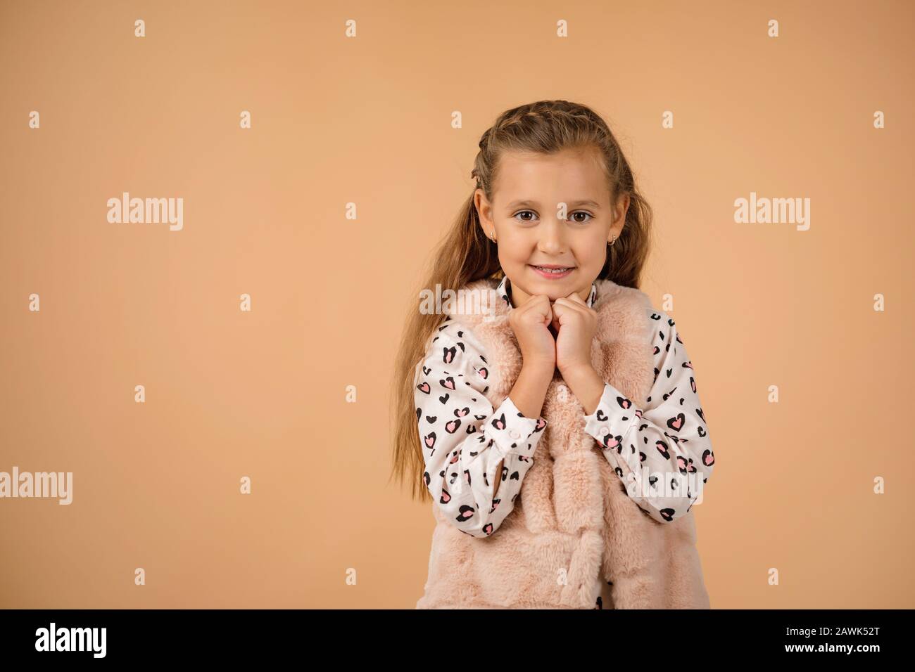 Cute smiling little child girl looking to camera on beige background ...