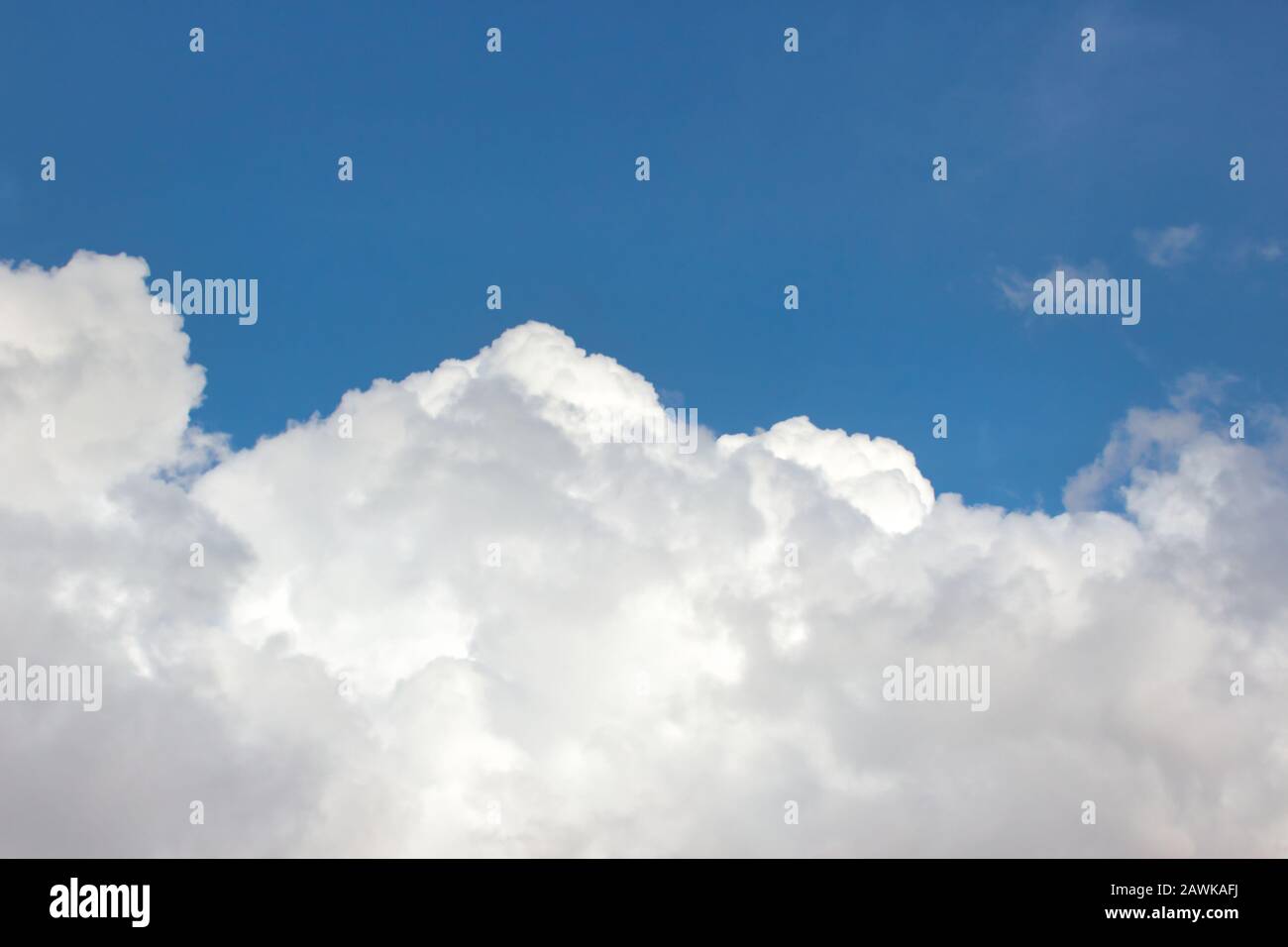 Big fluffy white clouds against a bright clear blue sky background Stock Photo - Alamy
