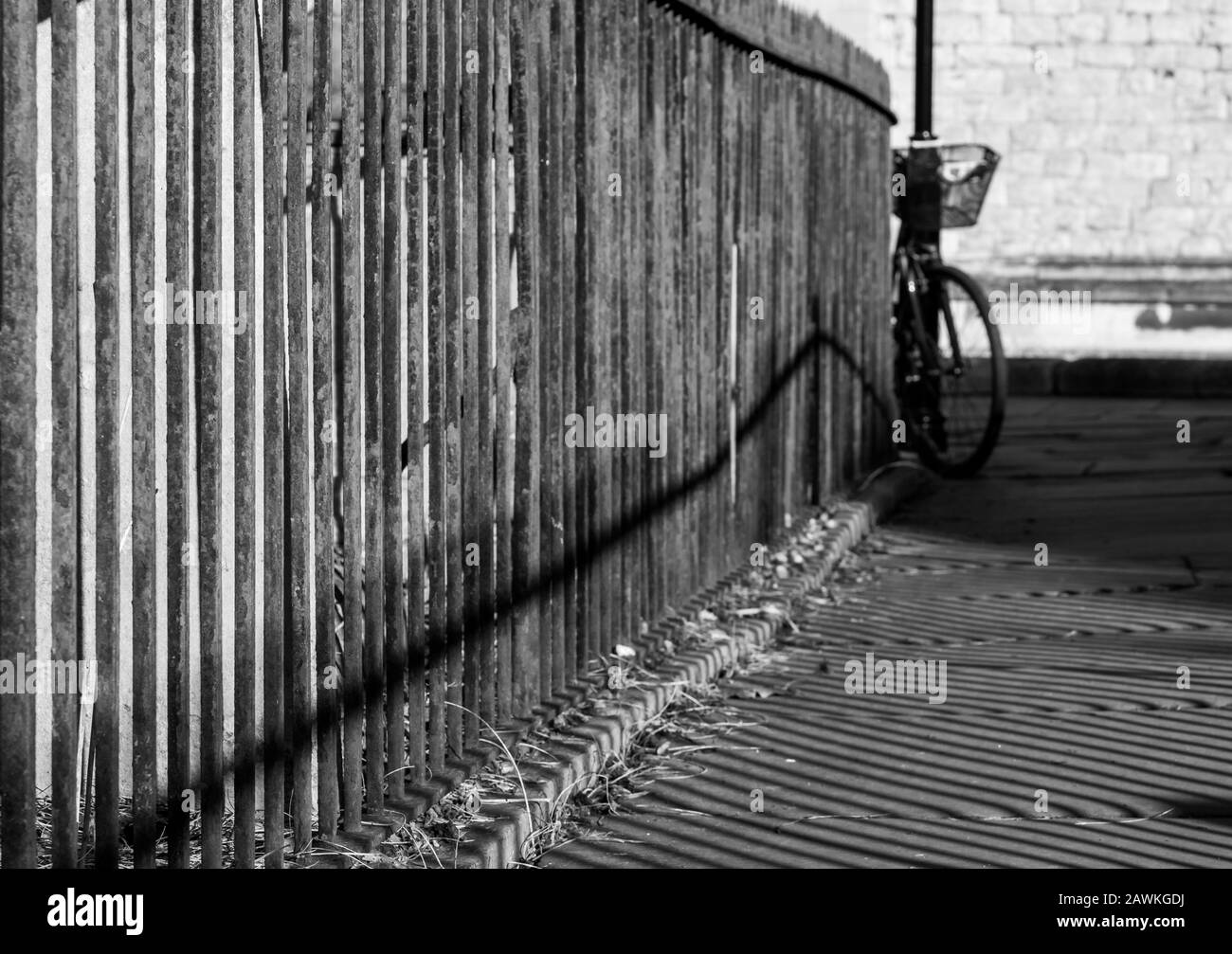 Close up of black painted railings and their shadows beside a pathway ...