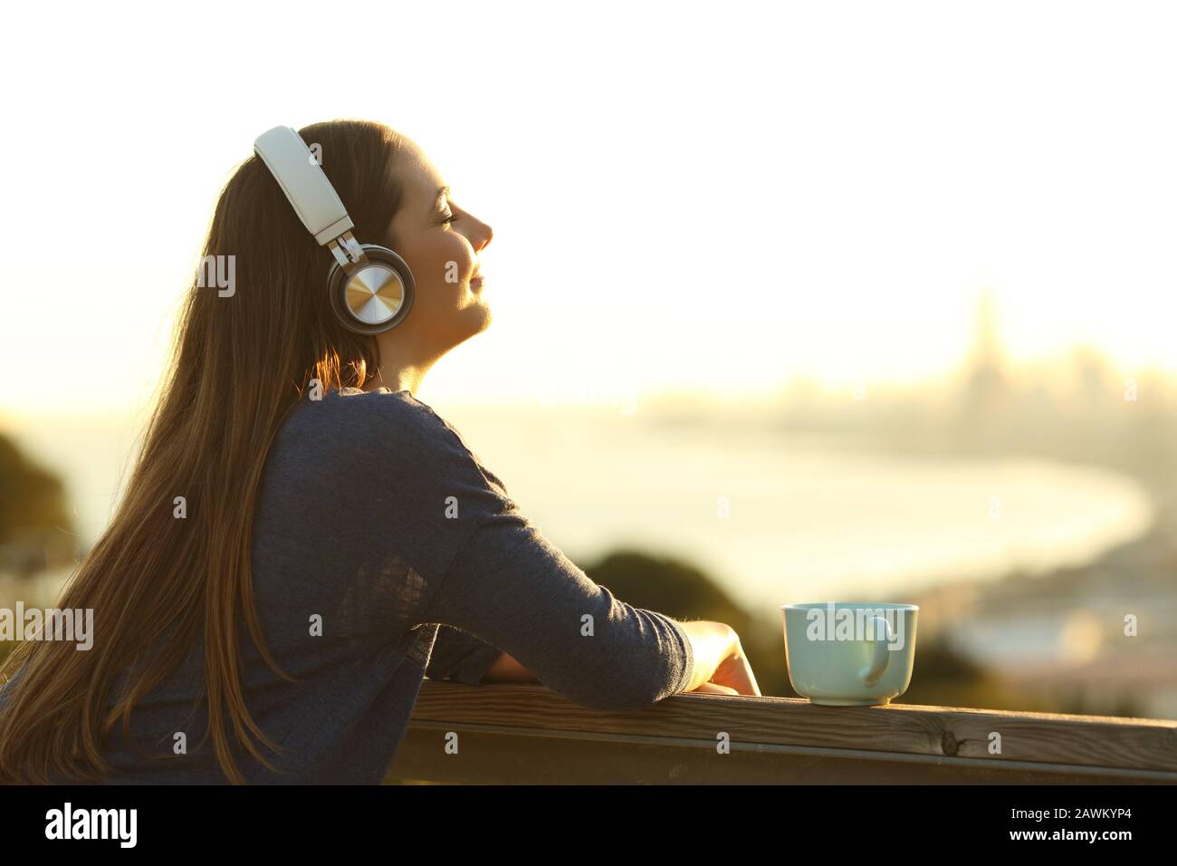 Relaxed woman listening to music breathing fresh air at sunset from a ...