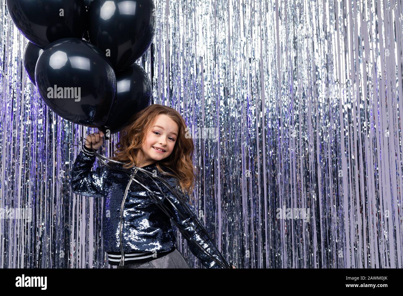 Attractive young girl holds with airy black helium balloons on a ...