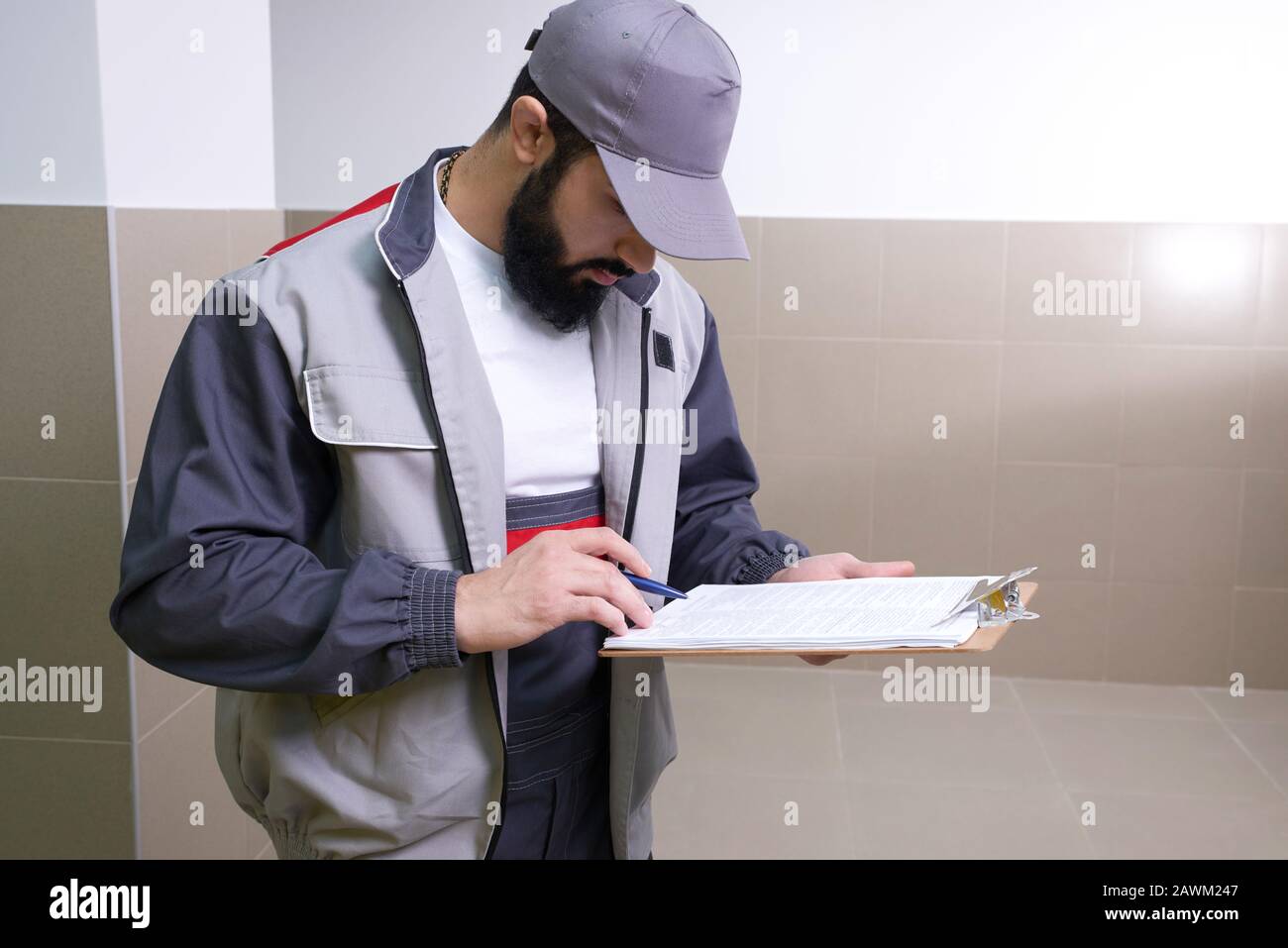 Concentrated young technician wearing overall standing and taking some ...