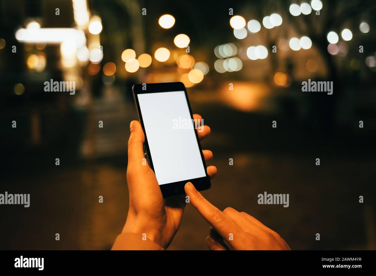 Woman's hands typing in mobile phone on city street at night, close-up ...