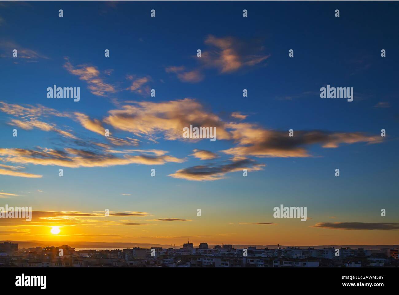 Scenic cityscape with golden evening sun goes down over the horizon ...