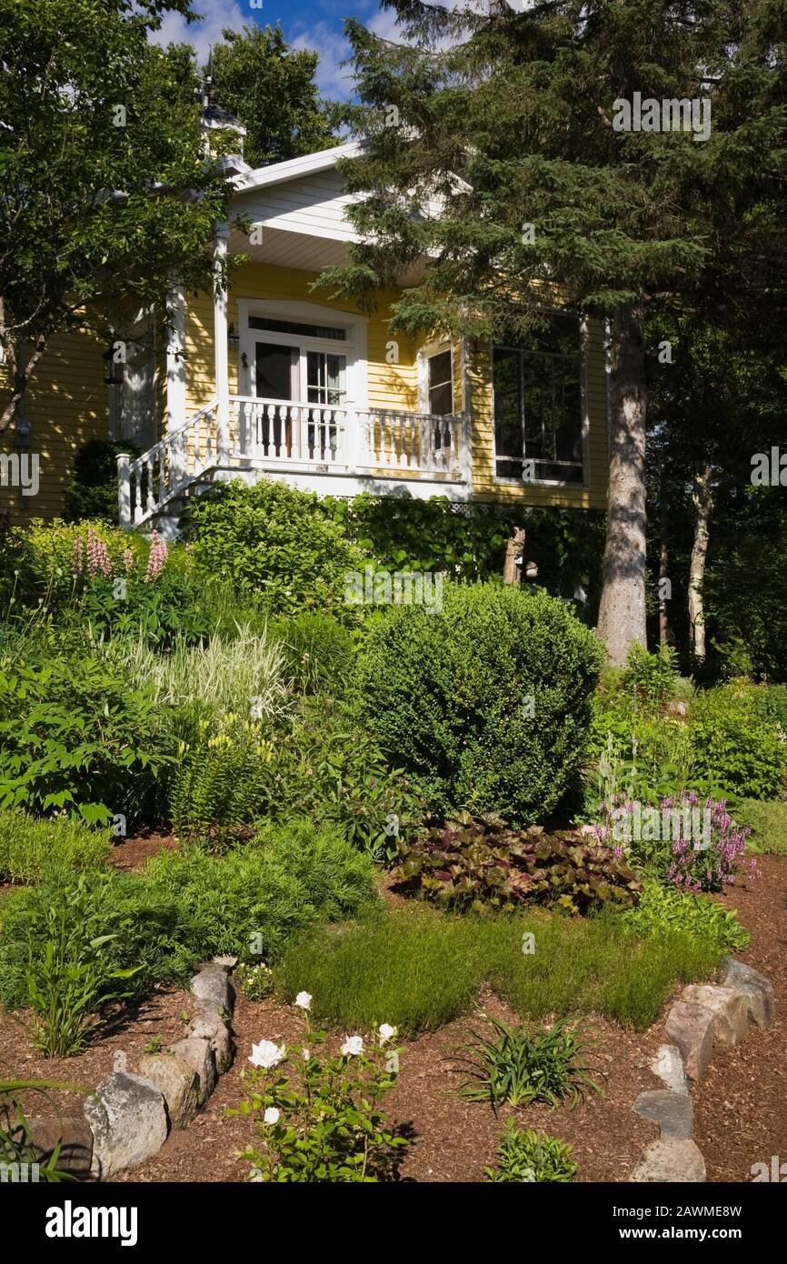 Yellow house with white trim and raised rock edged garden borders ...