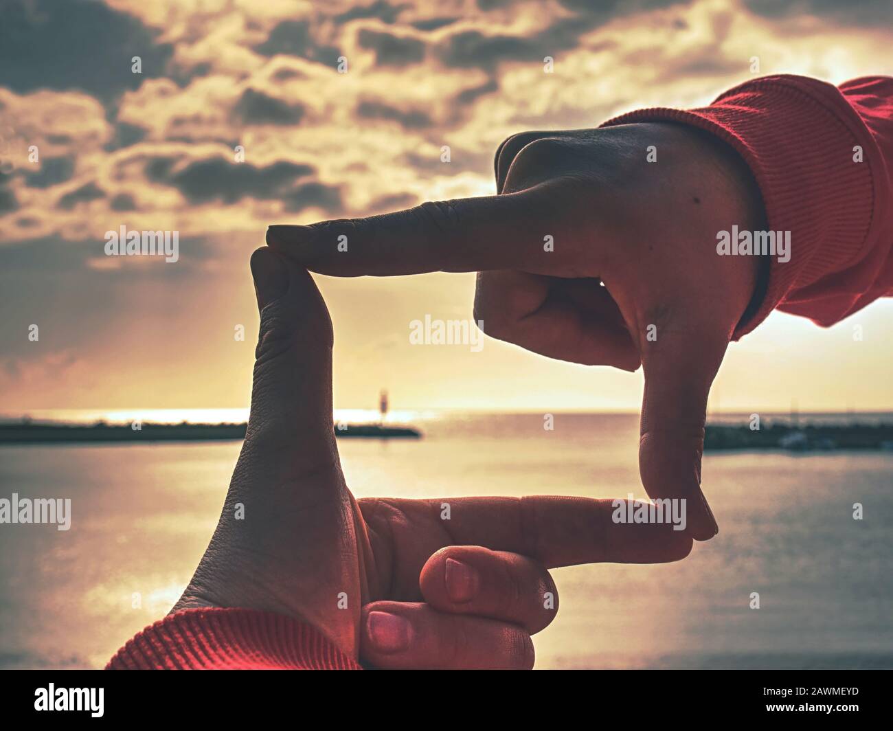 Hands making finger shape gesture, hand hold sun above stony fisherman ...