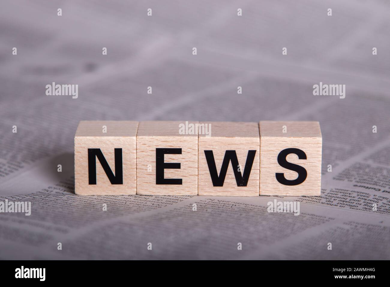 news, text on wooden cubes, newspaper as background Stock Photo - Alamy