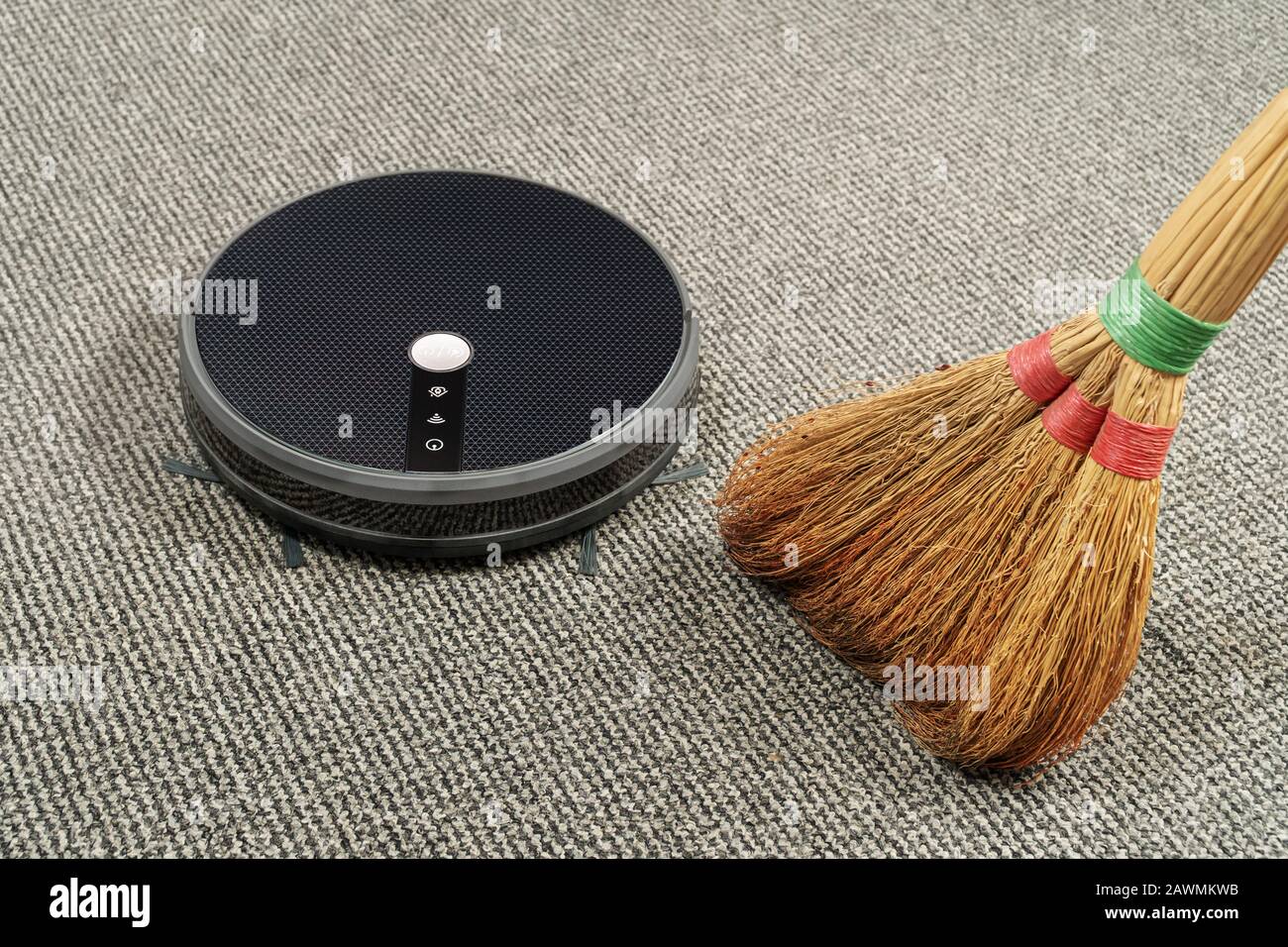 comparison of a vacuum cleaner robot and an old broom on a gray carpet ...