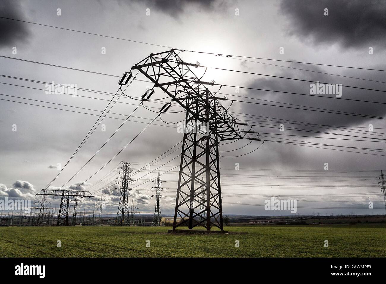 Sun hidden behind dramatic clouds and electricity pylons conducting ...