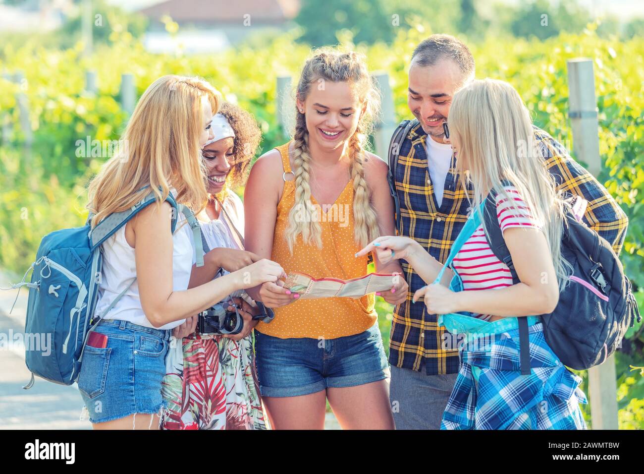 Multi-ethnic group of best friends looking at map while traveling in ...