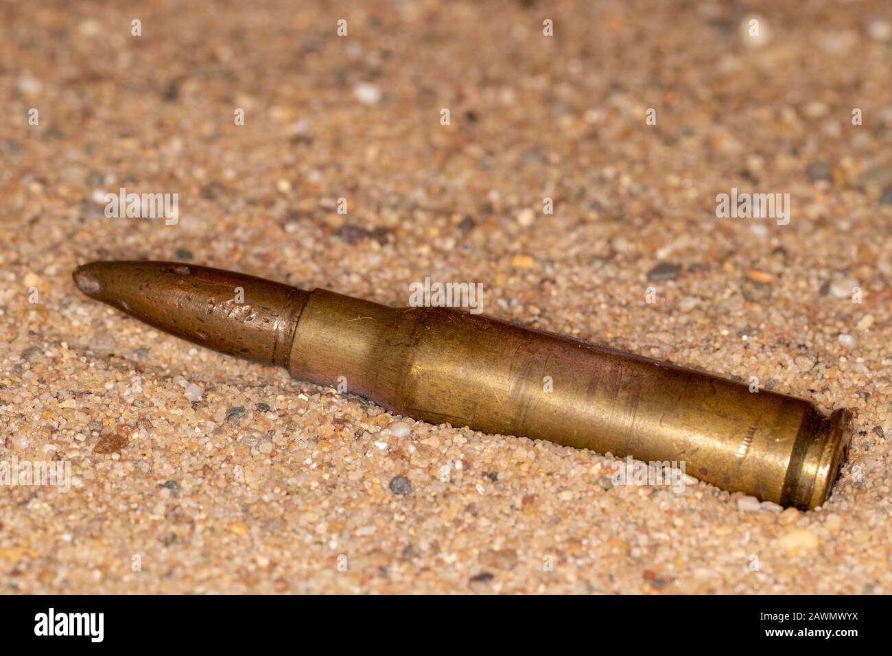 Copper live round in dry sand Stock Photo - Alamy