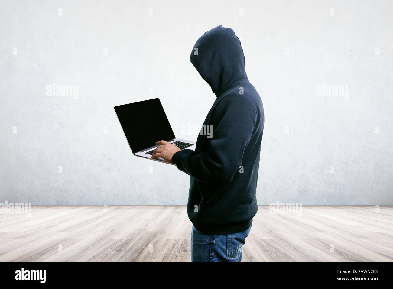 unknown hacker in the hood with laptop on the background of the room ...