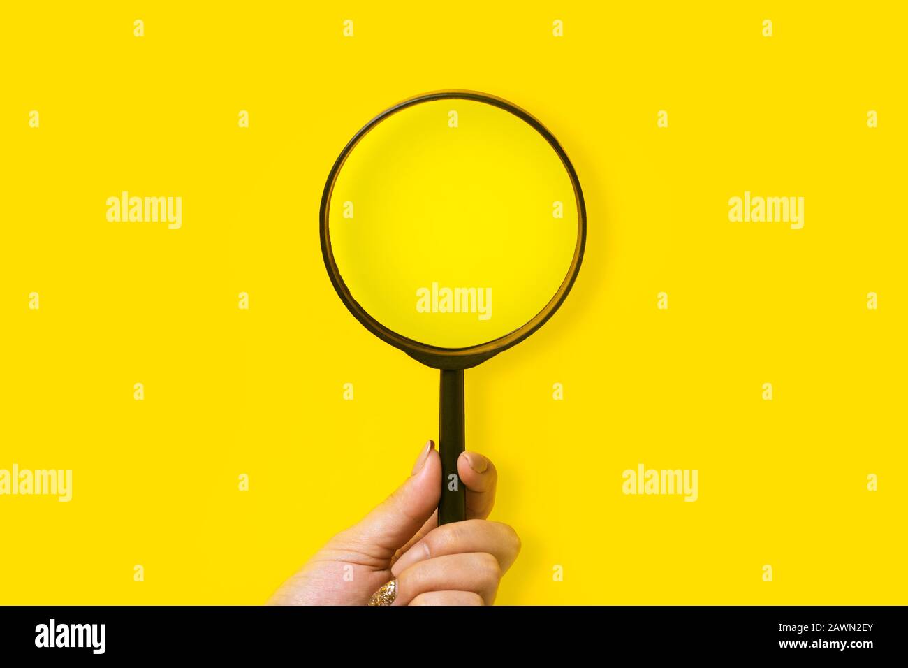 hand holding magnifier over yellow background Stock Photo - Alamy