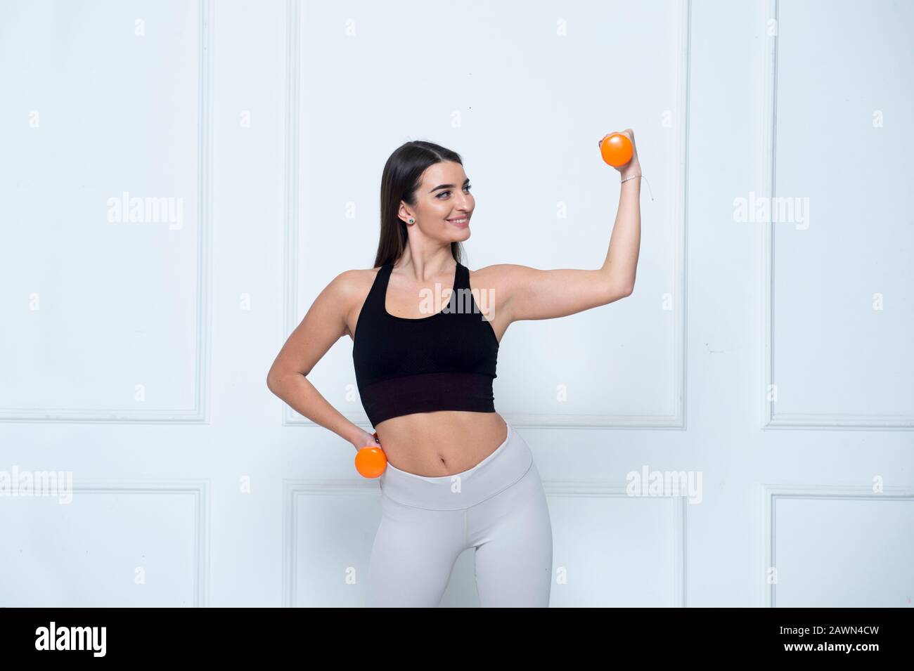 Woman with orange dumbbell fit slim abs body isolated on a white ...