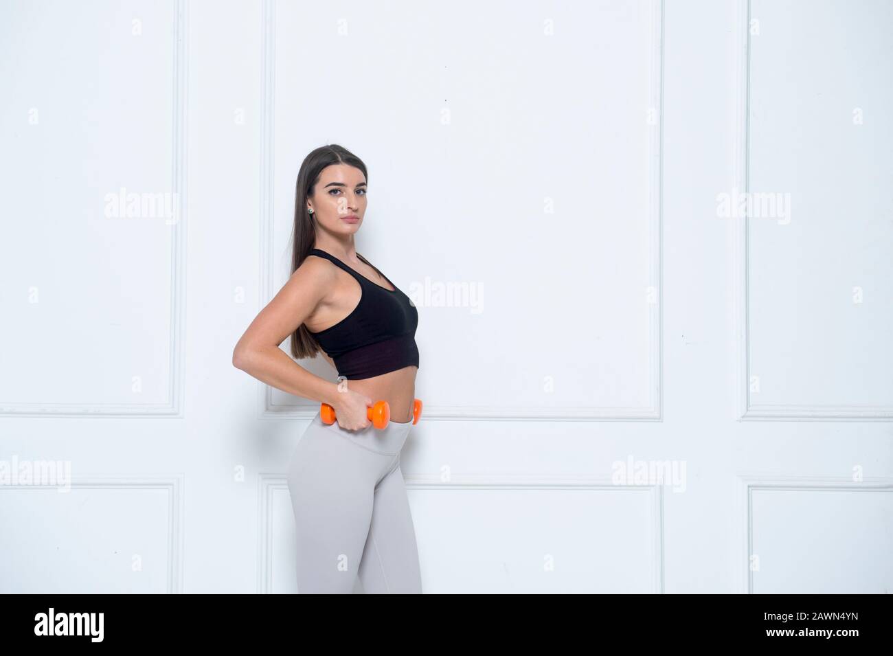 Woman with orange dumbbell fit slim abs body isolated on a white ...