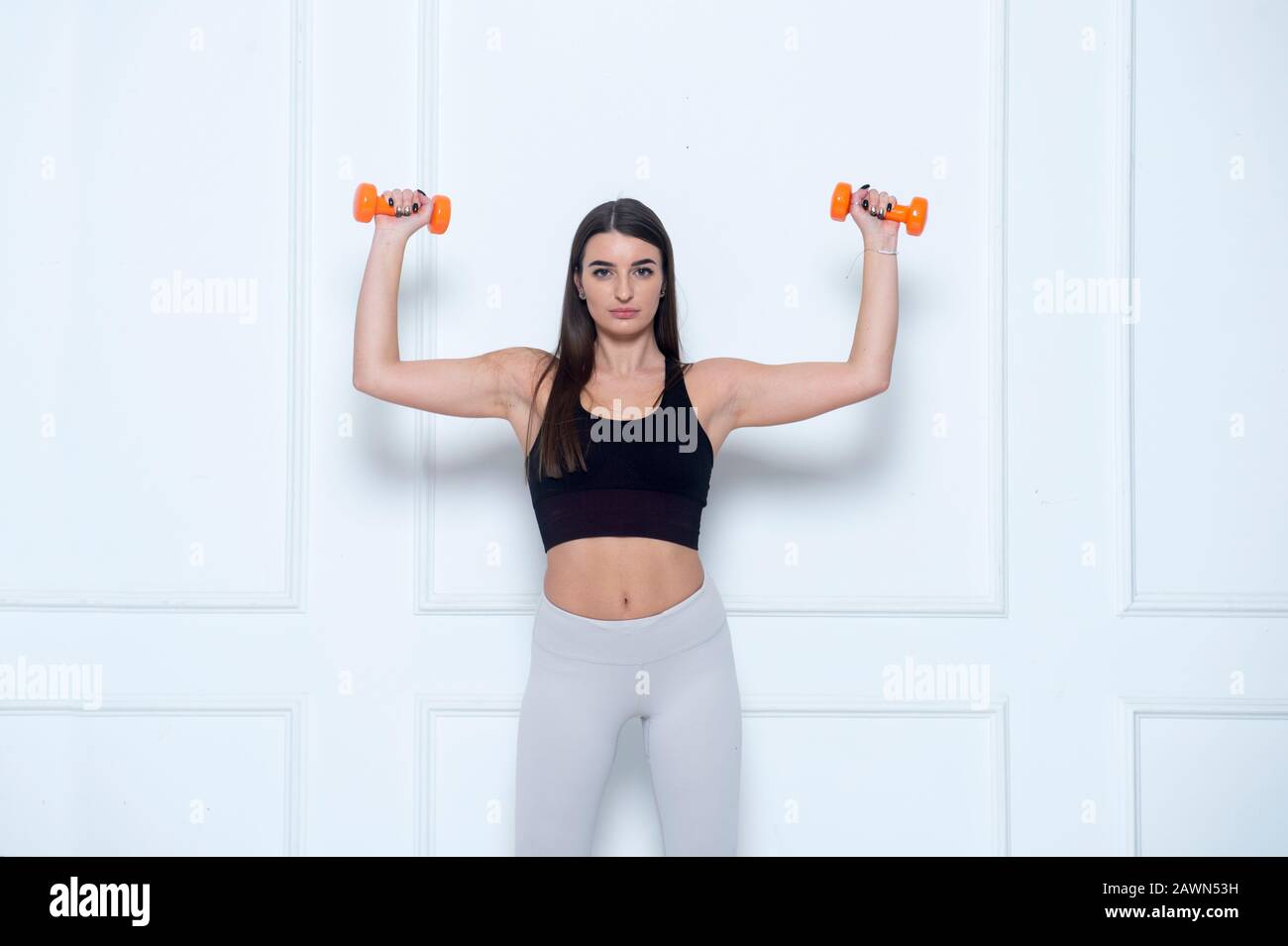 Woman with orange dumbbell fit slim abs body isolated on a white ...