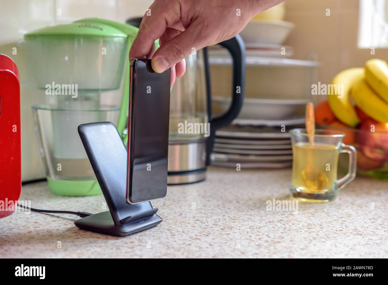 smartphone wireless charging on charging stand on kitchen tabletop ...