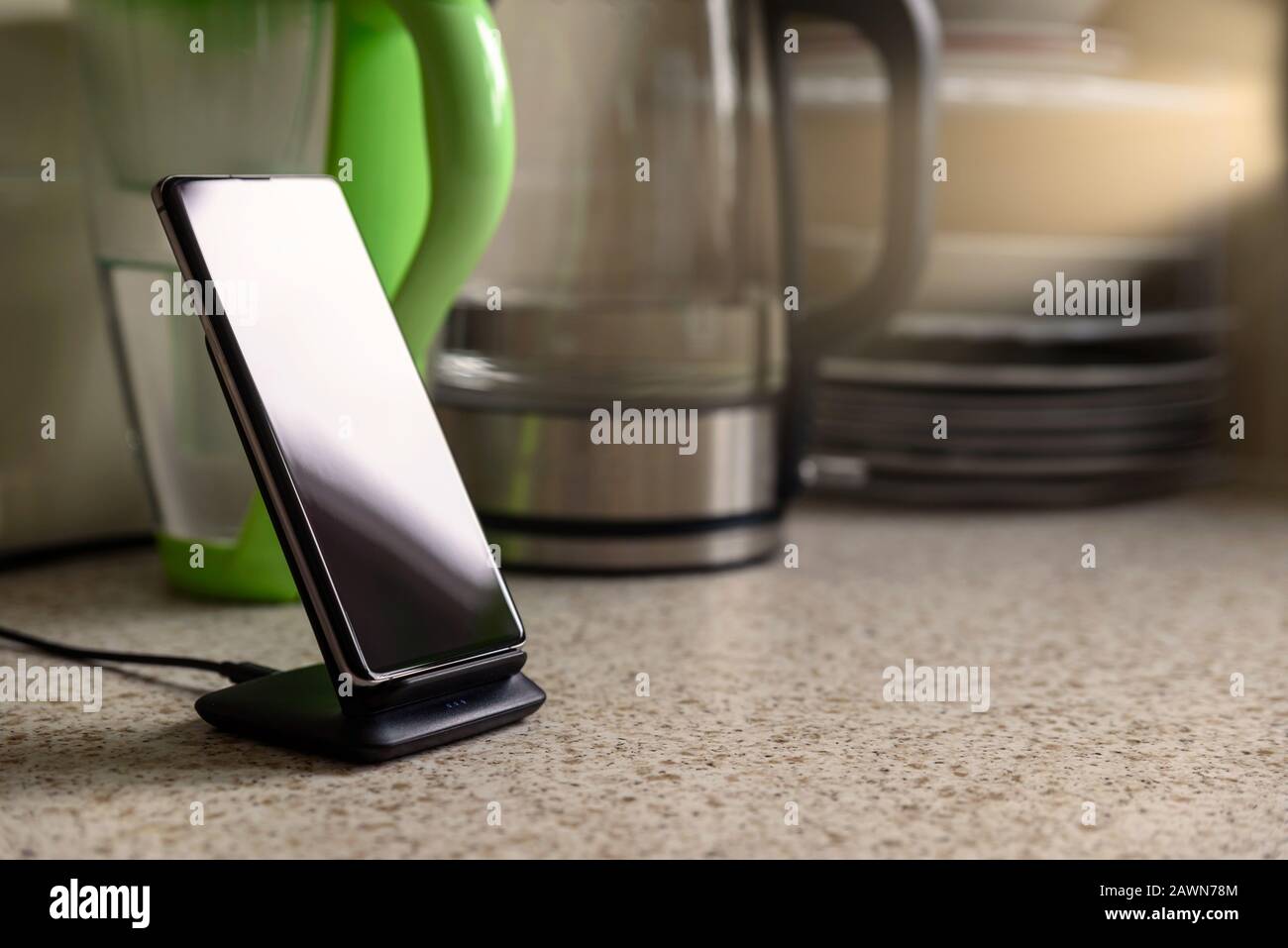 smartphone wireless charging on charging stand on kitchen tabletop ...