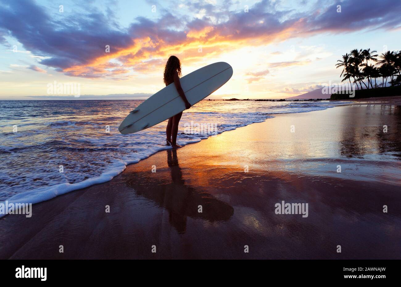 Female surfer watches sunset at White Rock, Maui, Hawaii Stock Photo ...